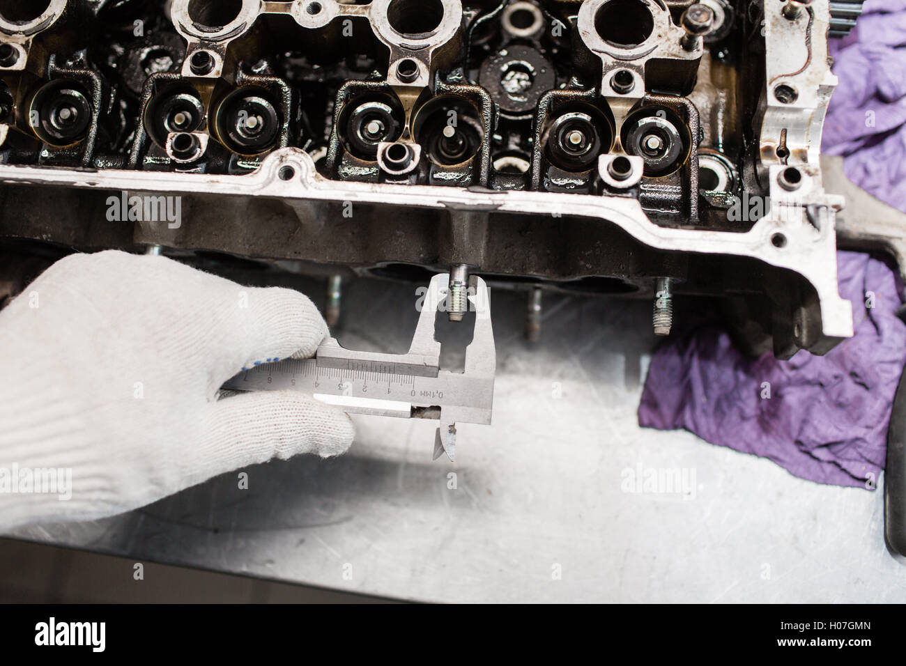 Mechanic, using a calipher, to check the thickness. Full engine major ...