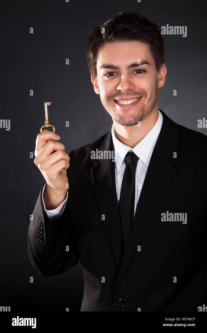 Smiling businessman holding a golden key Stock Photo - Alamy