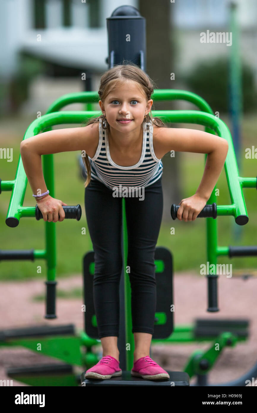 Little girl is engaged in fitness equipment outdoor Stock Photo - Alamy
