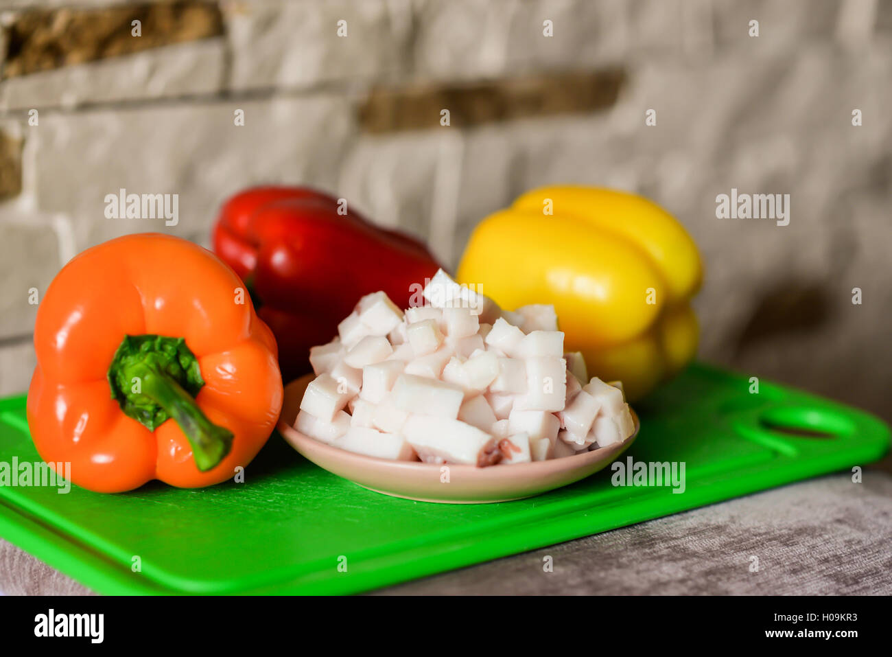 Lard cubes in small plate with colored bell peppers on green plastic ...
