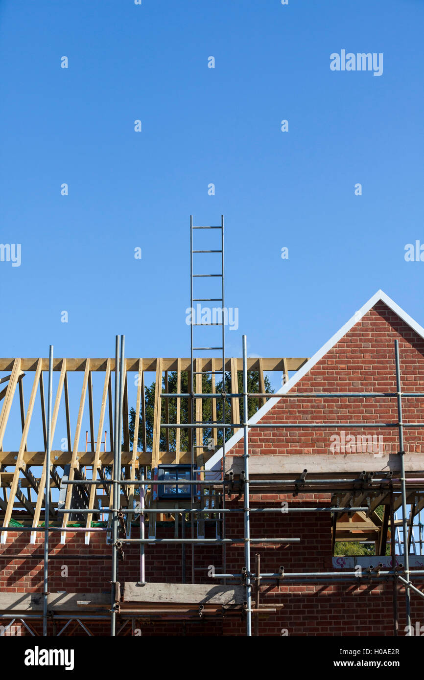 A half built house, roof open to the weather with scaffolding and ...