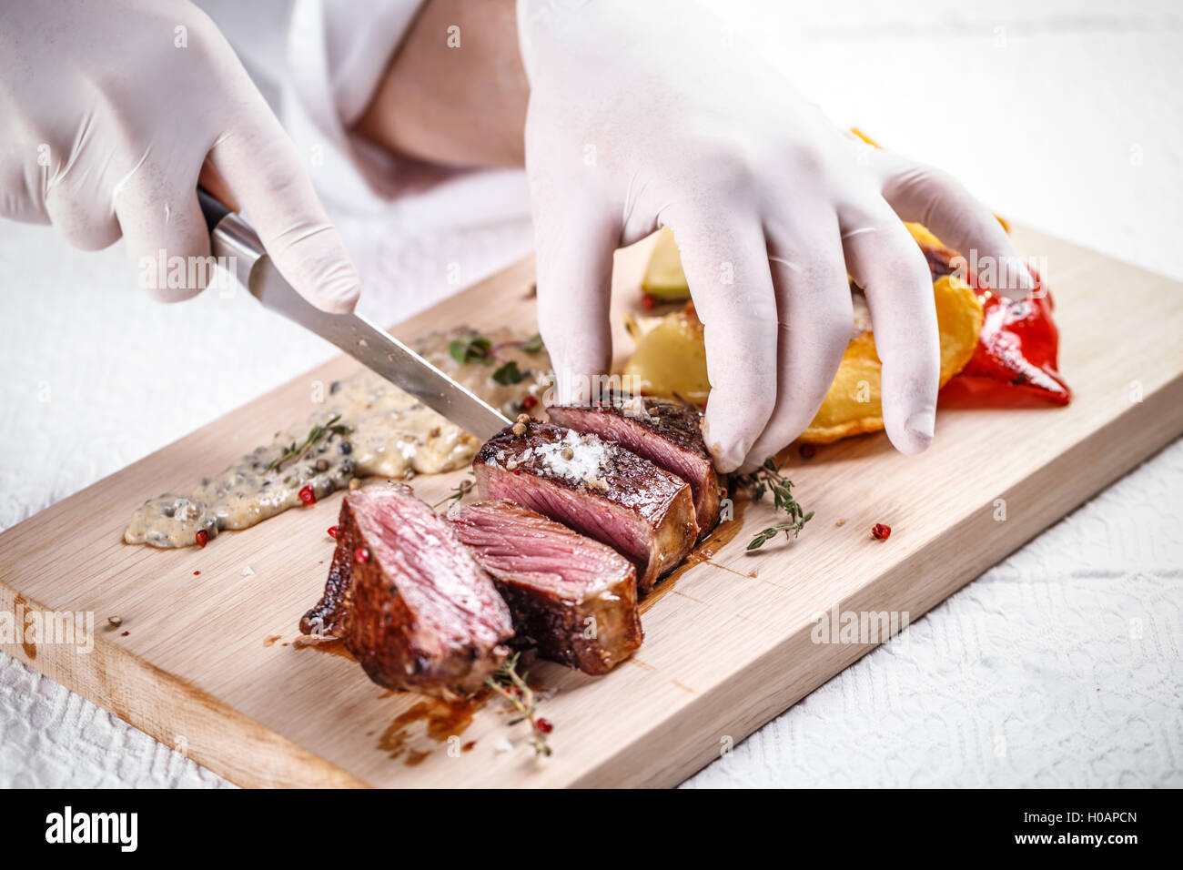 Chef in restaurant kitchen cutting beef steak Stock Photo - Alamy