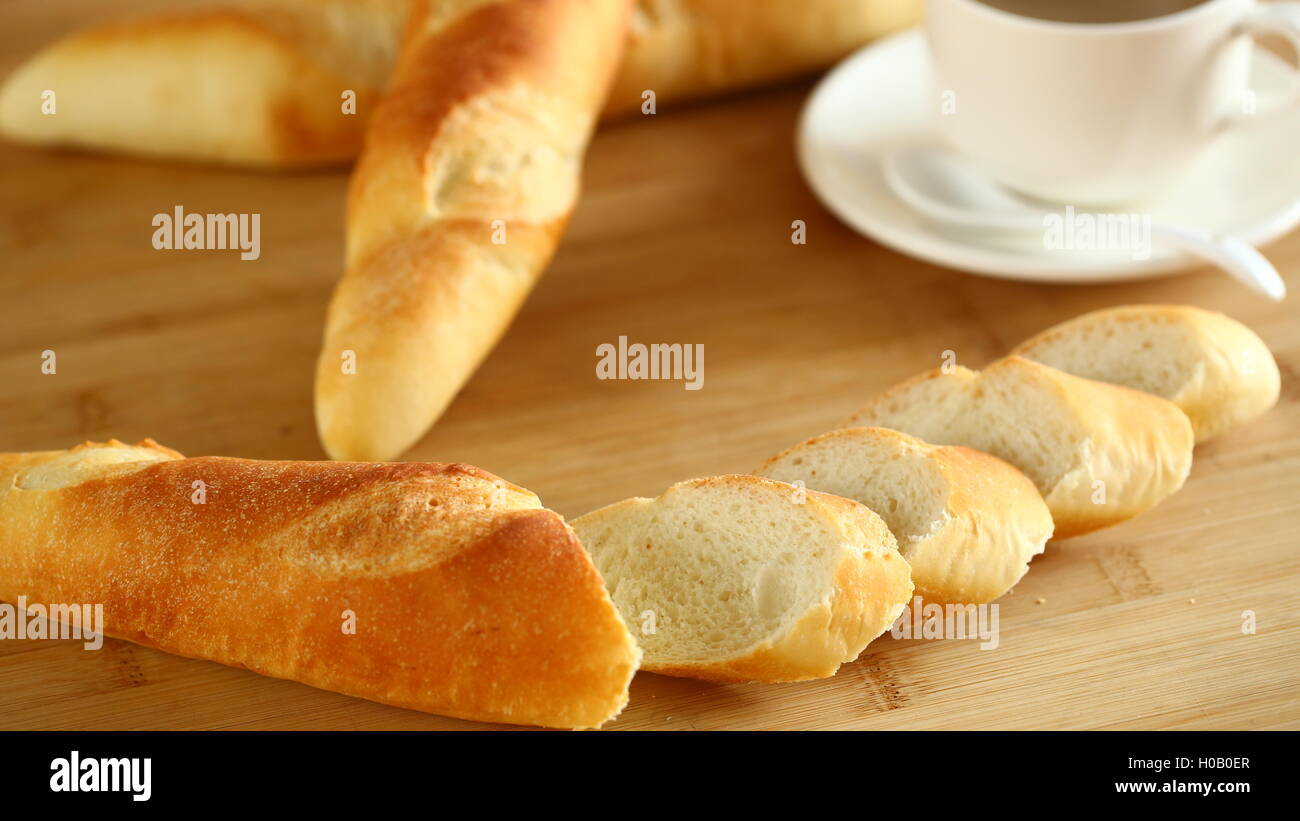 Chopped long bread on wooden cutting board Stock Photo - Alamy