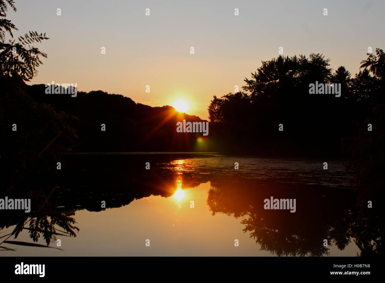 A summer sunset in Pure Michigan, with a lake reflection of the trees ...