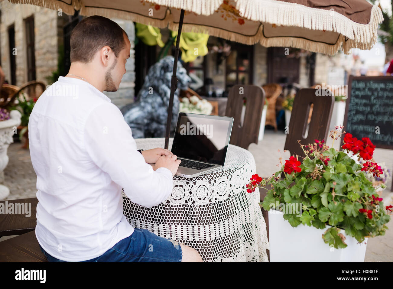 Man using a modern portable computer on an outdoor table, street on ...