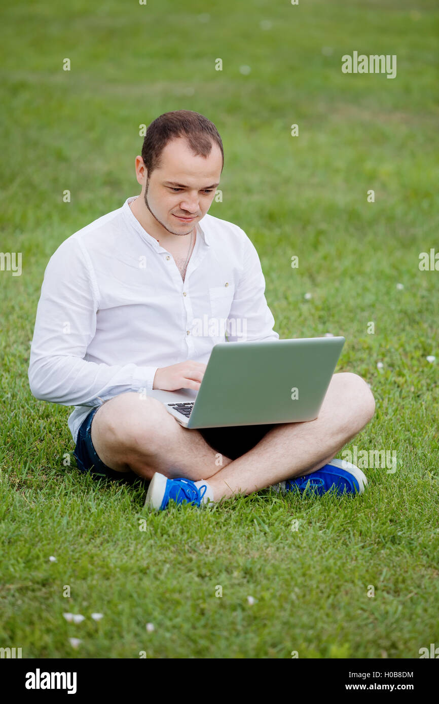 A young man with laptop working outdoor Stock Photo - Alamy