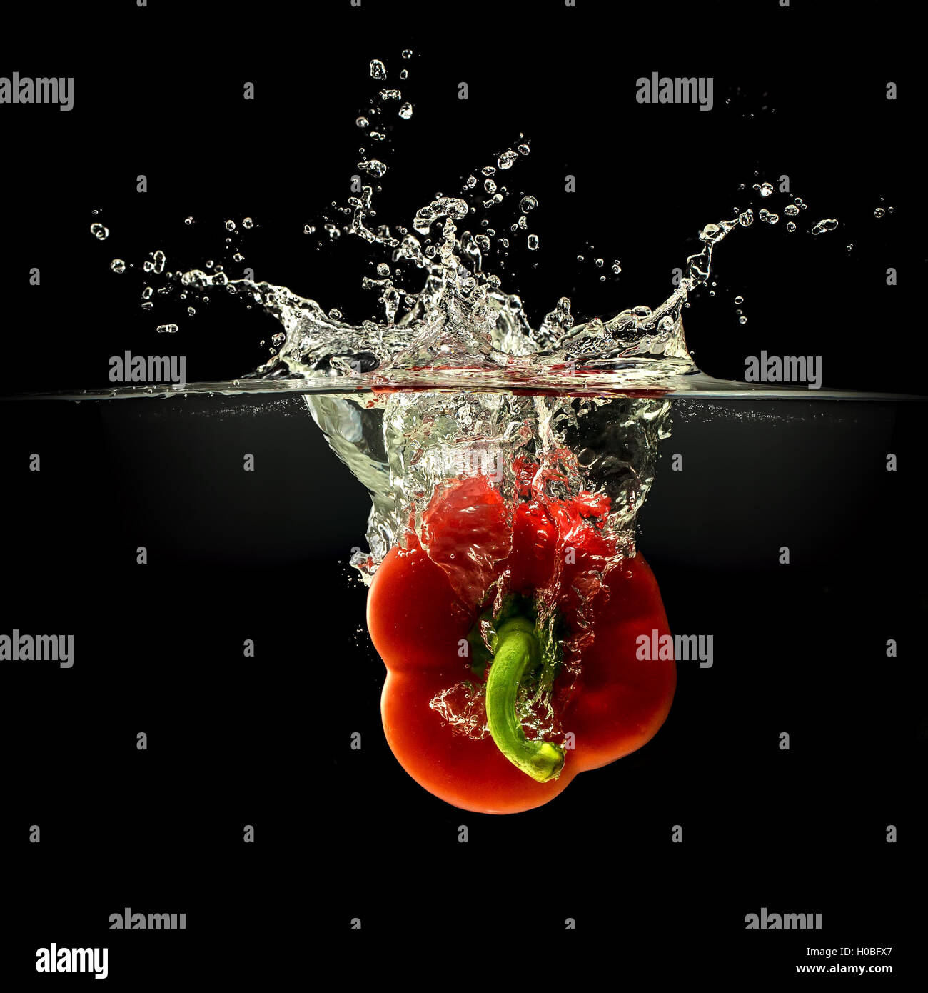 Red bell pepper falling in water, black background Stock Photo - Alamy