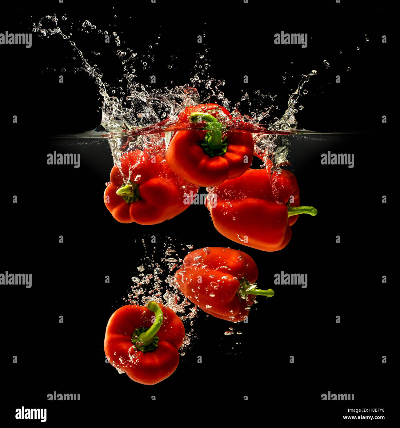 Group of bell pepper falling in water on black Stock Photo - Alamy