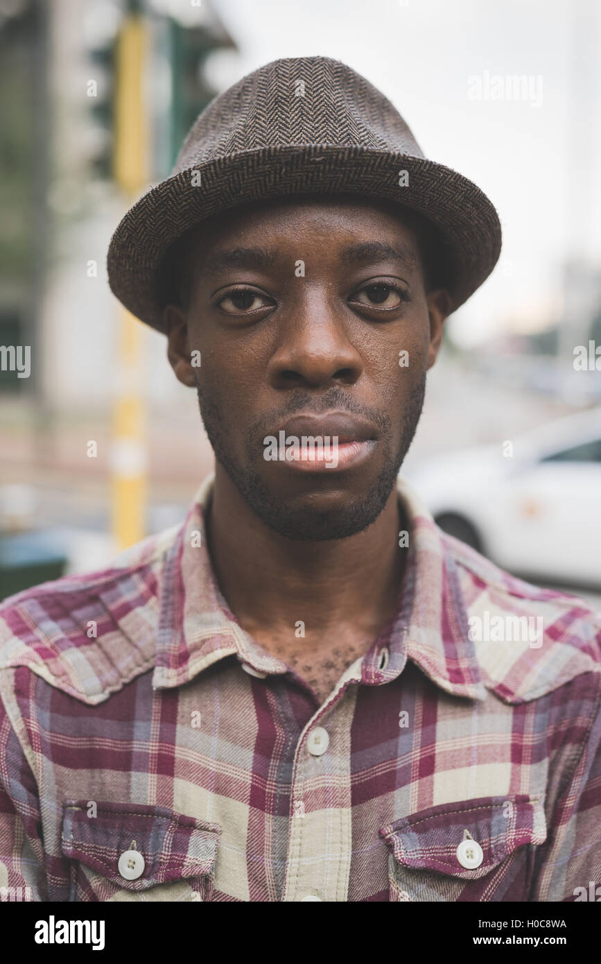 Half length portrait of young handsome afro black man looking in camera, holding bag, pensive ...