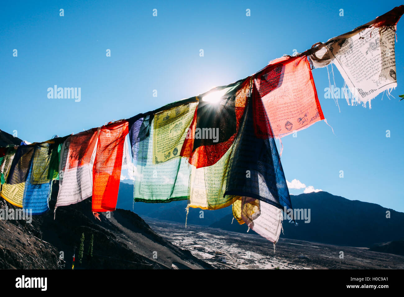 Colorful prayer flags with sun shining through one of prayer flags in ...