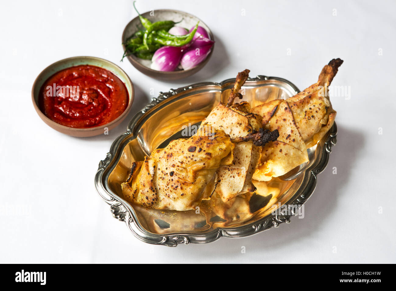 Breaded rabbit legs with sauce and onion, chili on white background ...