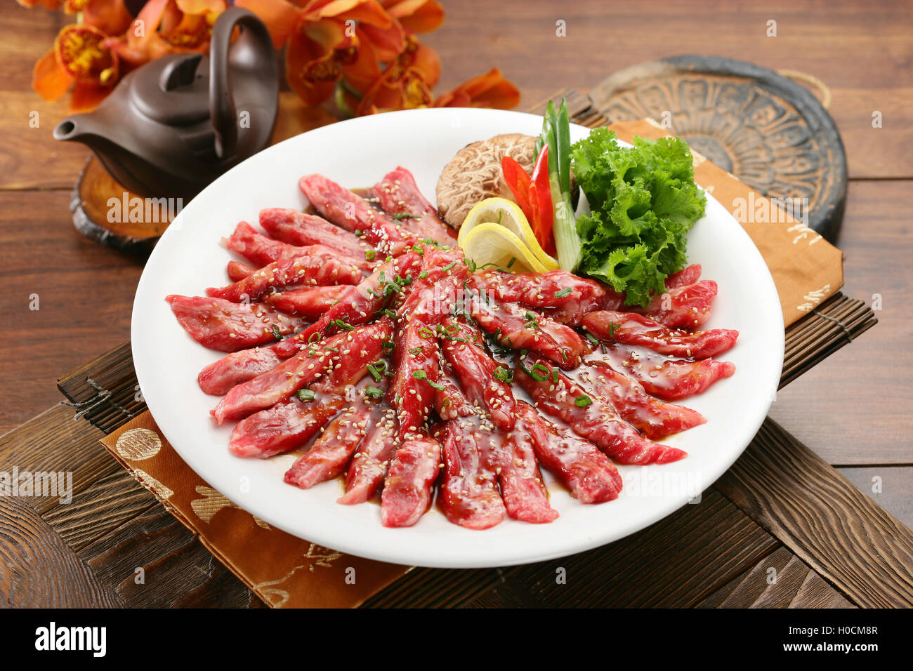 Seasoned sliced beef on white plate with lemon, mushroom and salad ...