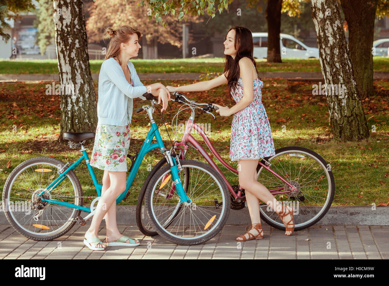 The two young girls with bicycles in park Stock Photo - Alamy