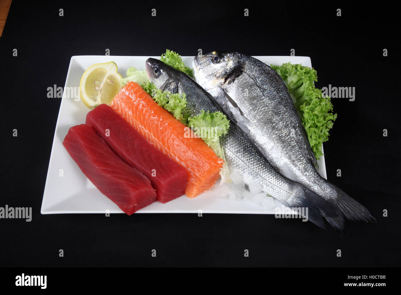 plate of mixed fish on a black background Stock Photo - Alamy