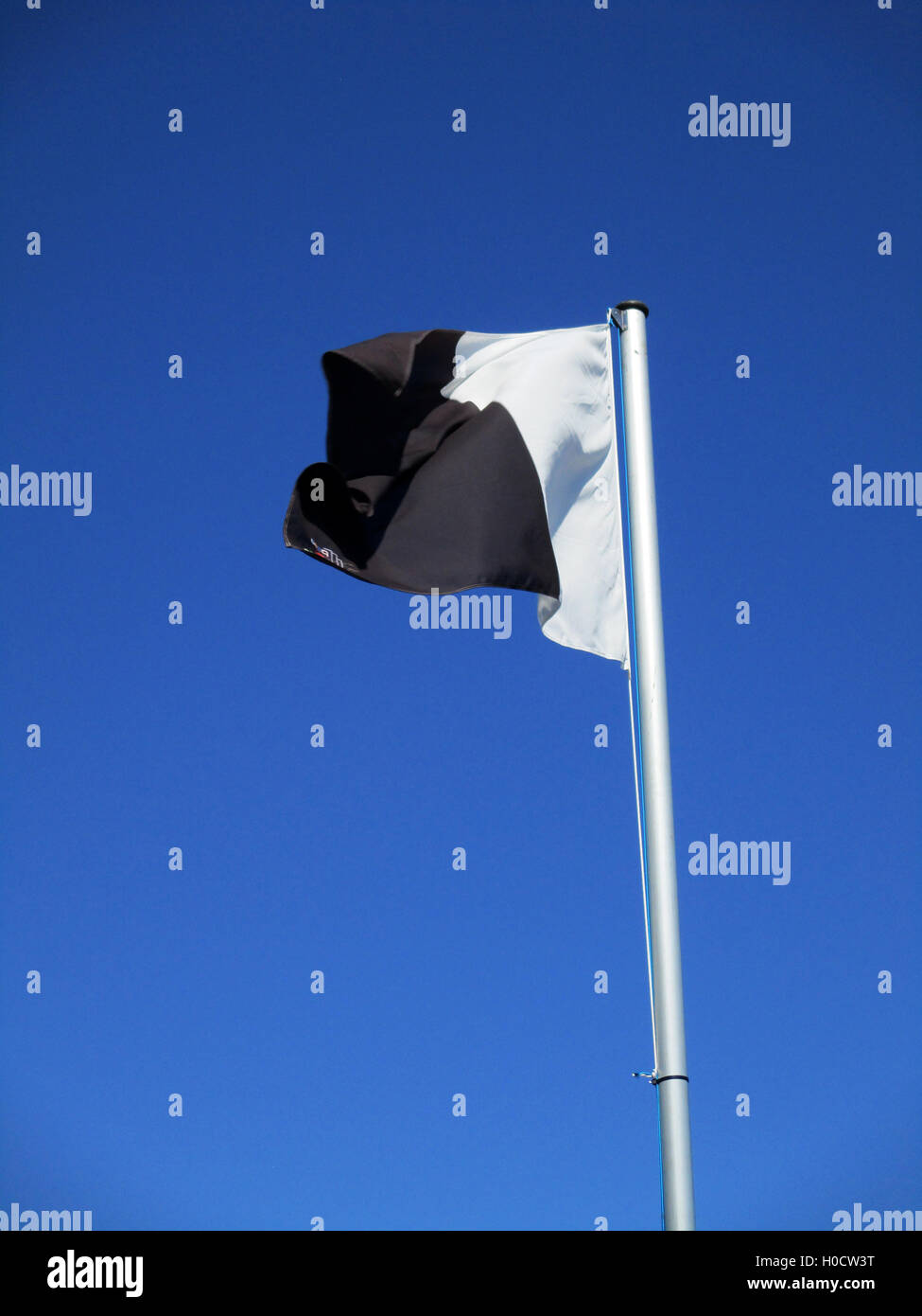 white and black flag flying in the blue sky Stock Photo - Alamy