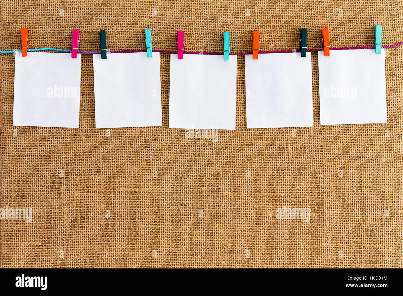 Neat row of hanging blank white notepads suspended by clothespins from ...