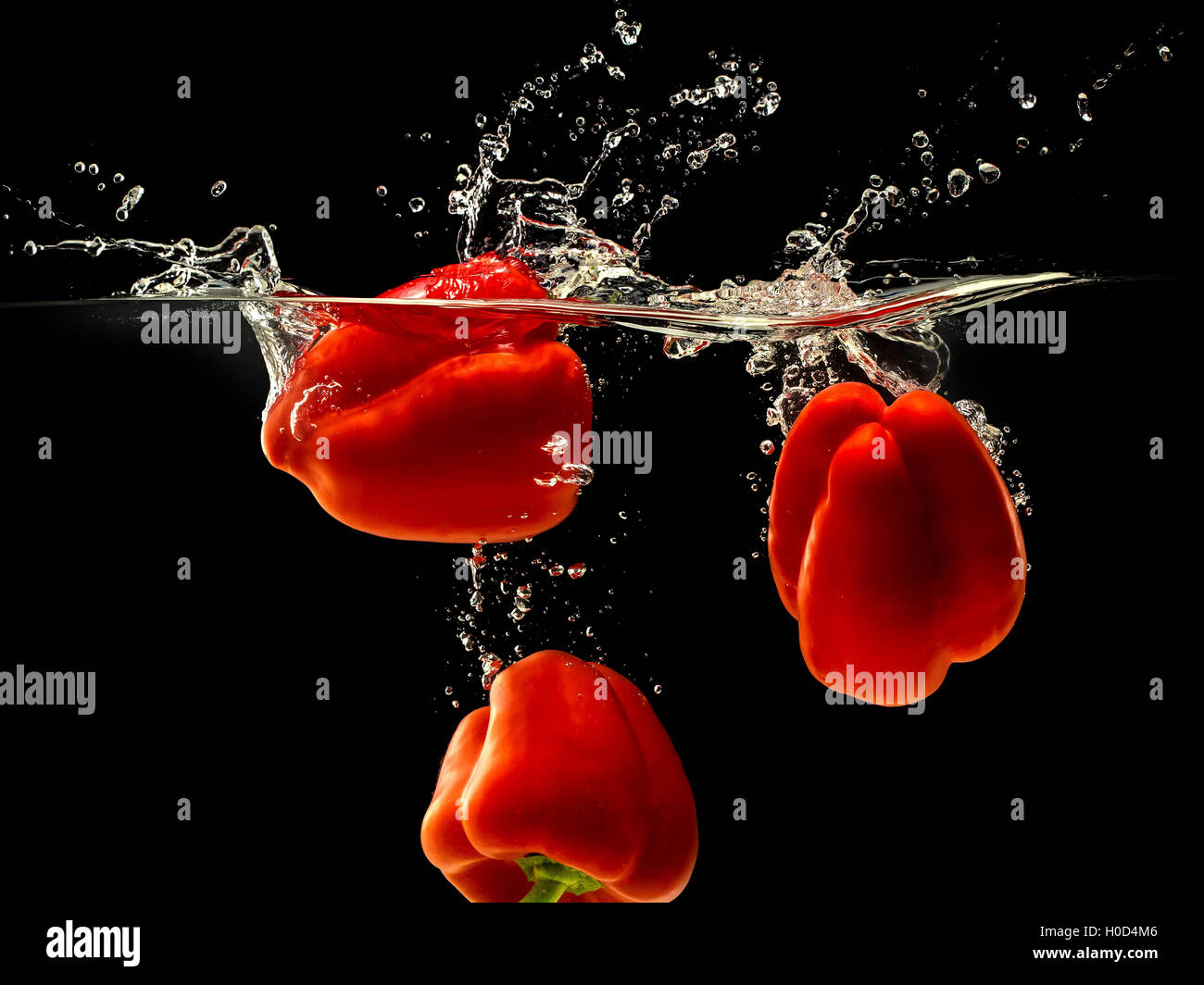 Group of bell pepper falling in water on black Stock Photo - Alamy