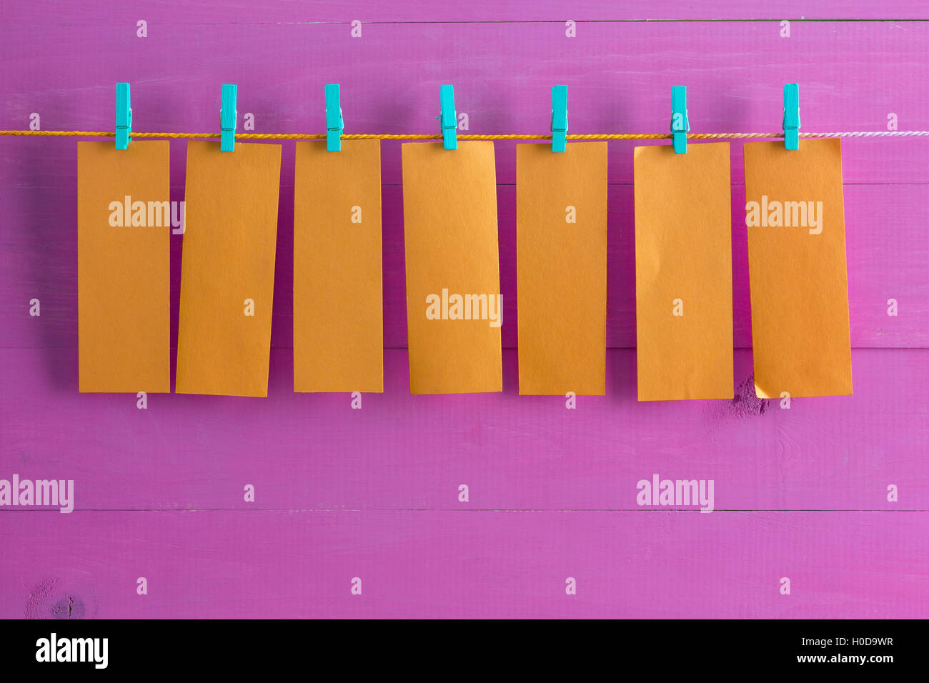 Blank orange note pad sheets hanging from string over painted purple ...