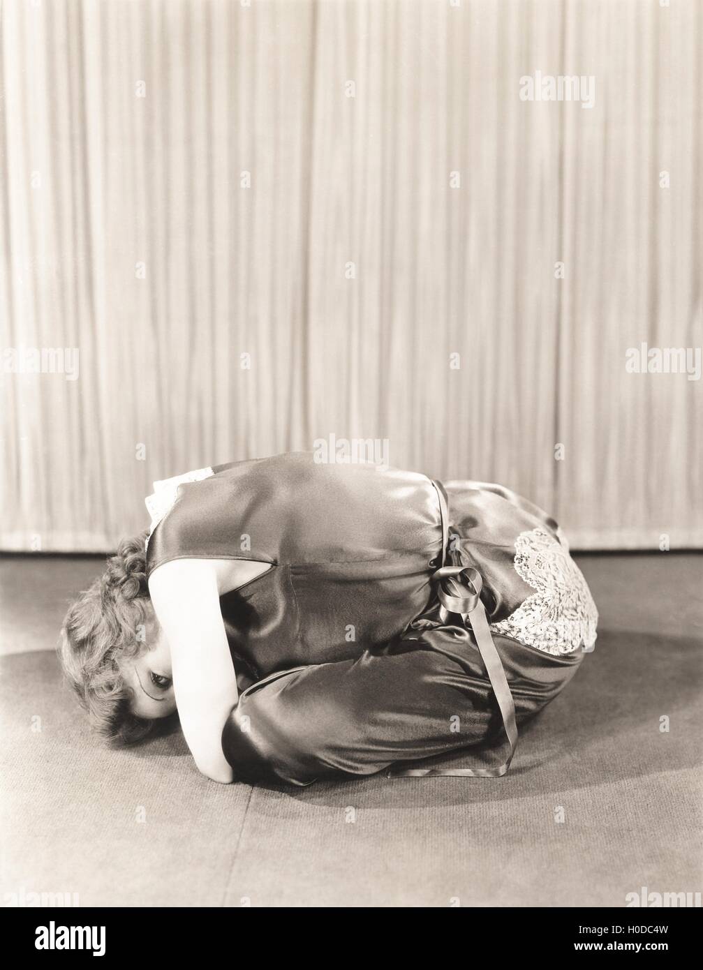 Woman curled up on floor Stock Photo - Alamy