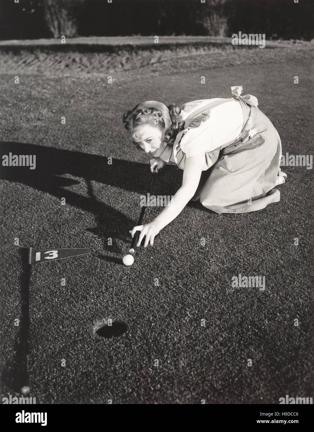 Female golfer crouching to line up a shot Stock Photo - Alamy