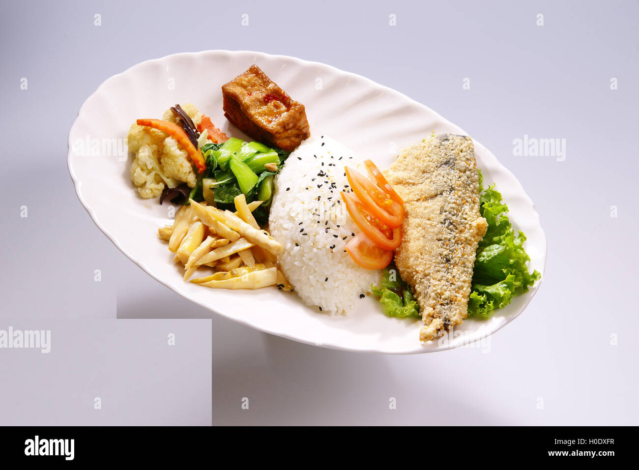Fried fish steak rice with vegetable on white plate in white background ...