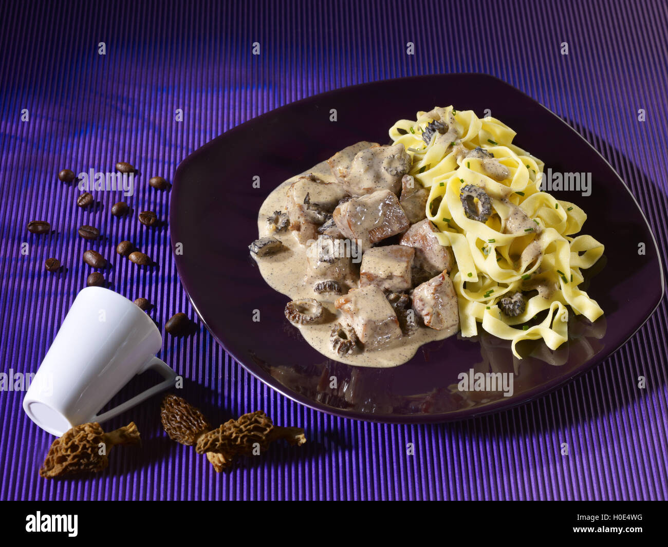 Veal with morel sauce on black plate on blue background Stock Photo - Alamy