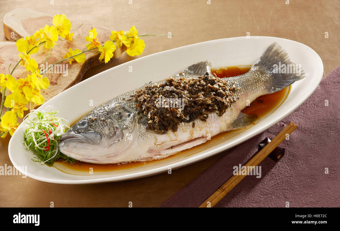 Meicai steamed fresh water fish grouper with sauce on white plate Stock ...