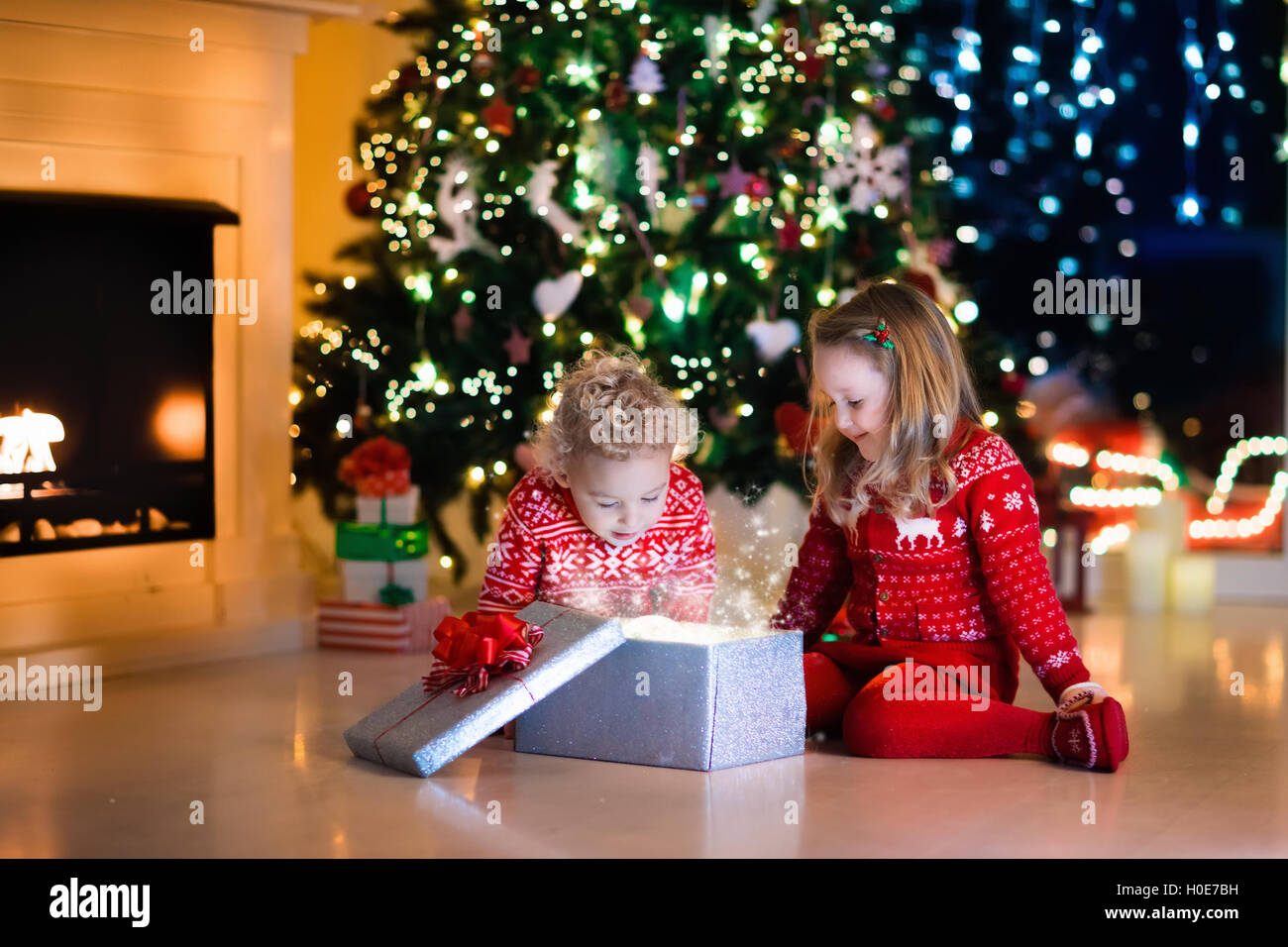 Family on Christmas eve at fireplace. Kids opening Xmas presents ...
