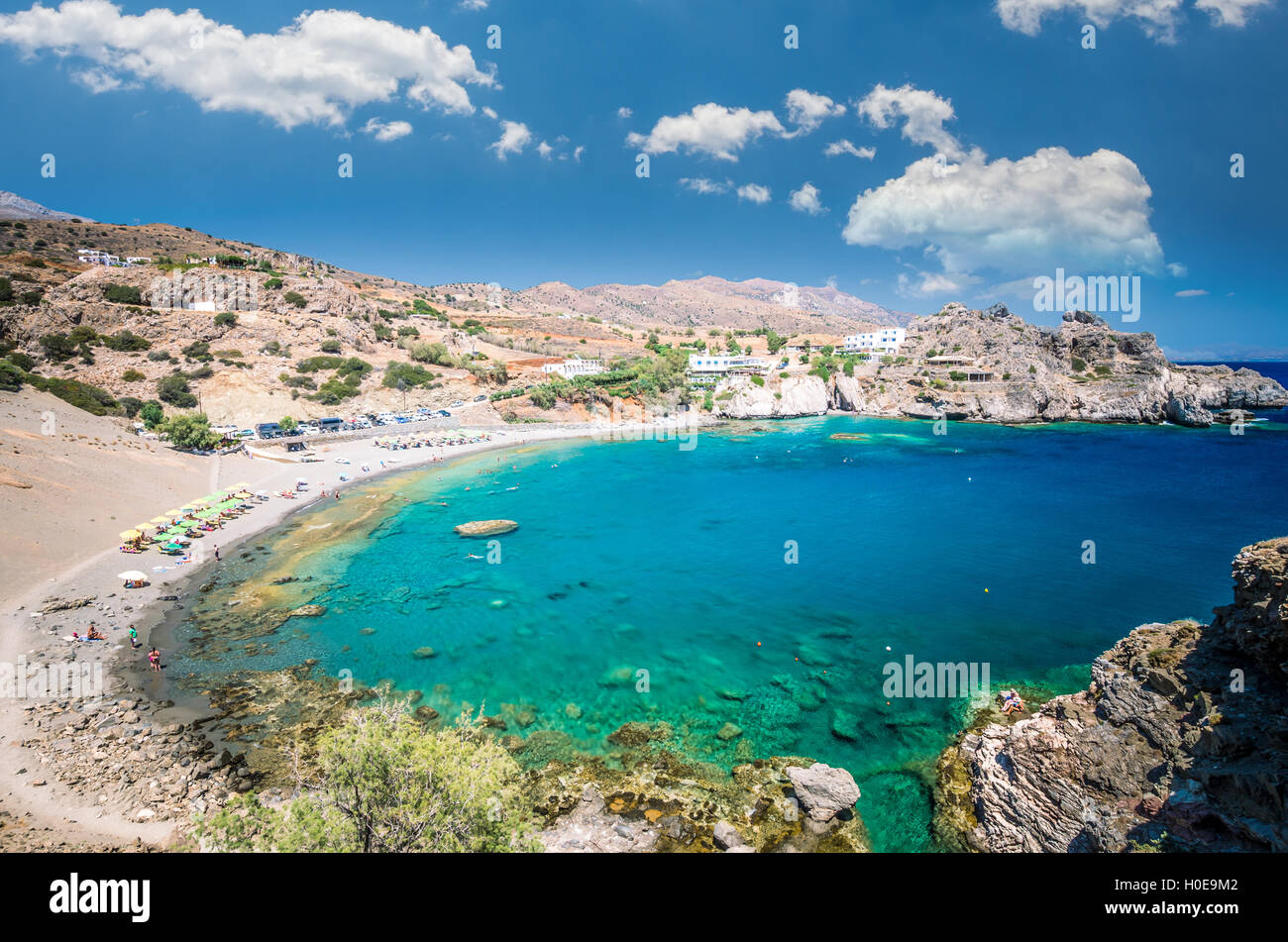 Agios Pavlos Beach in Crete island, Greece. Tourists relax and bath in crystal clear water of St ...