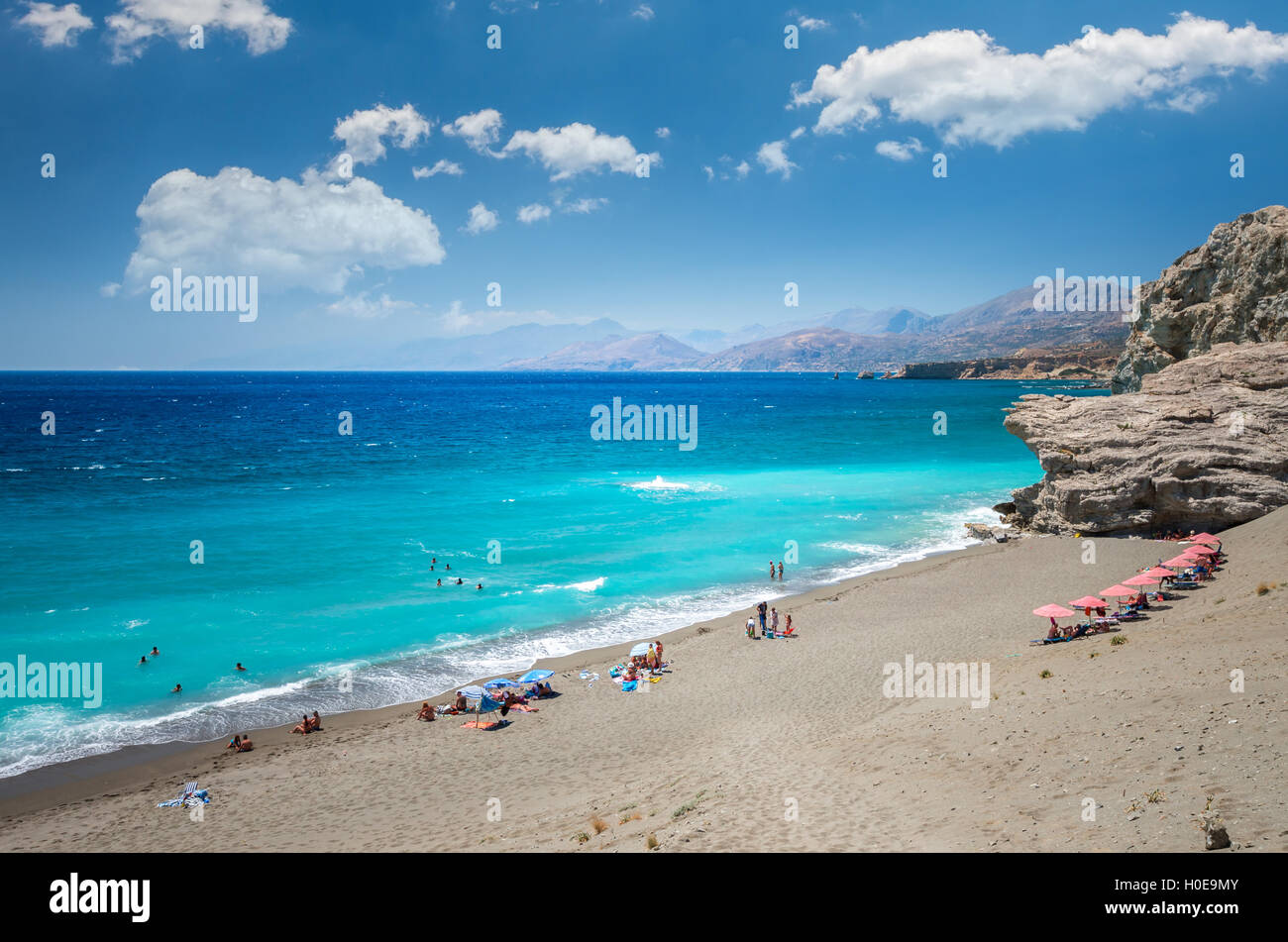 Agios Pavlos Beach in Crete island, Greece. Tourists relax and bath in crystal clear water of St ...