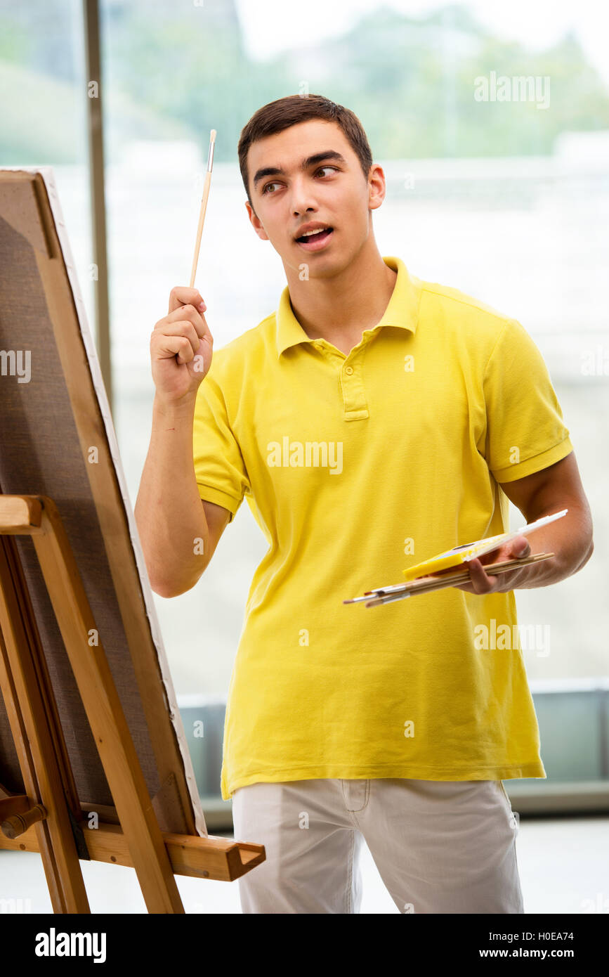 Young male artist drawing pictures in bright studio Stock Photo - Alamy