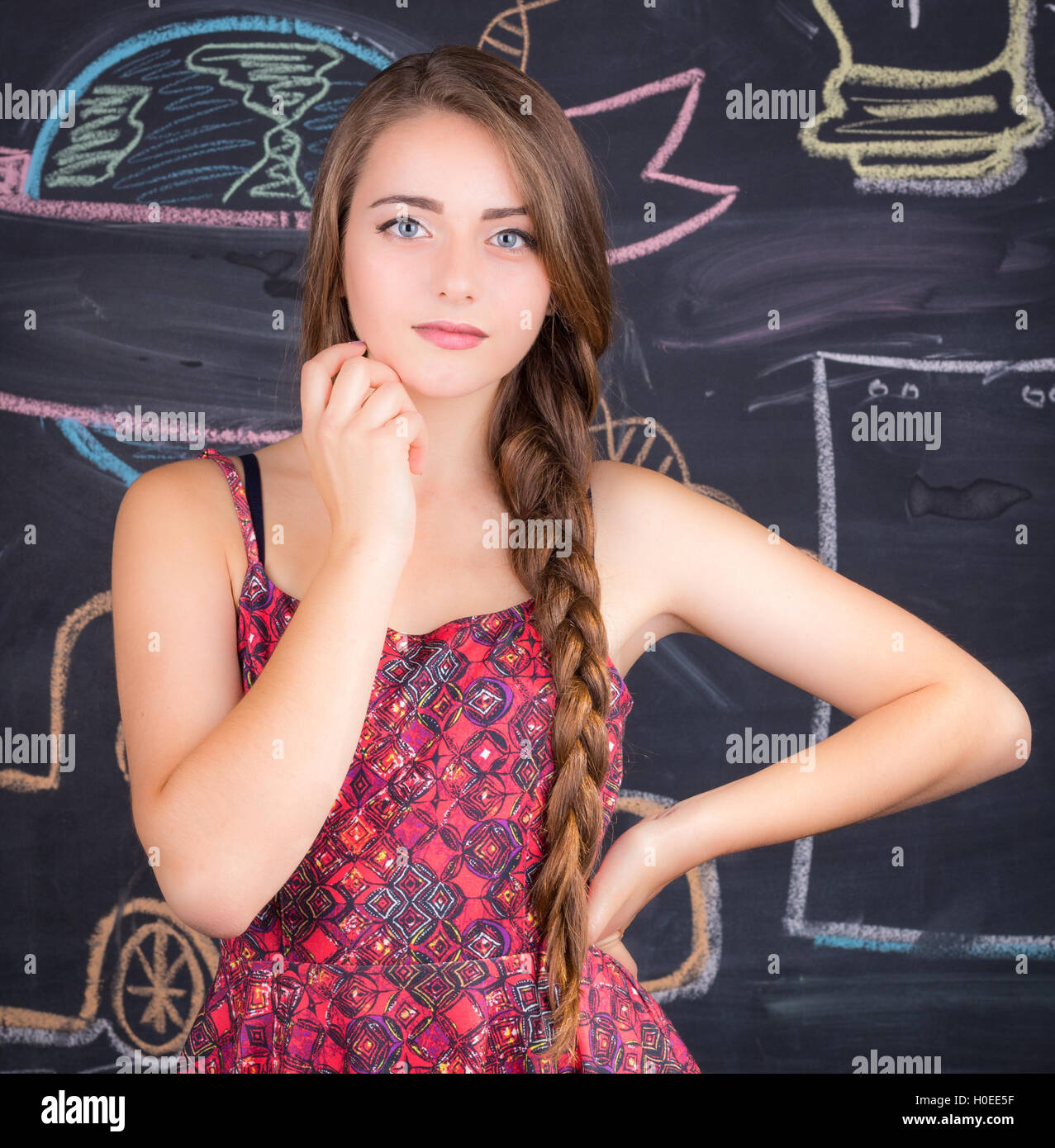Young student girl in red dress poses in front of school classroom ...