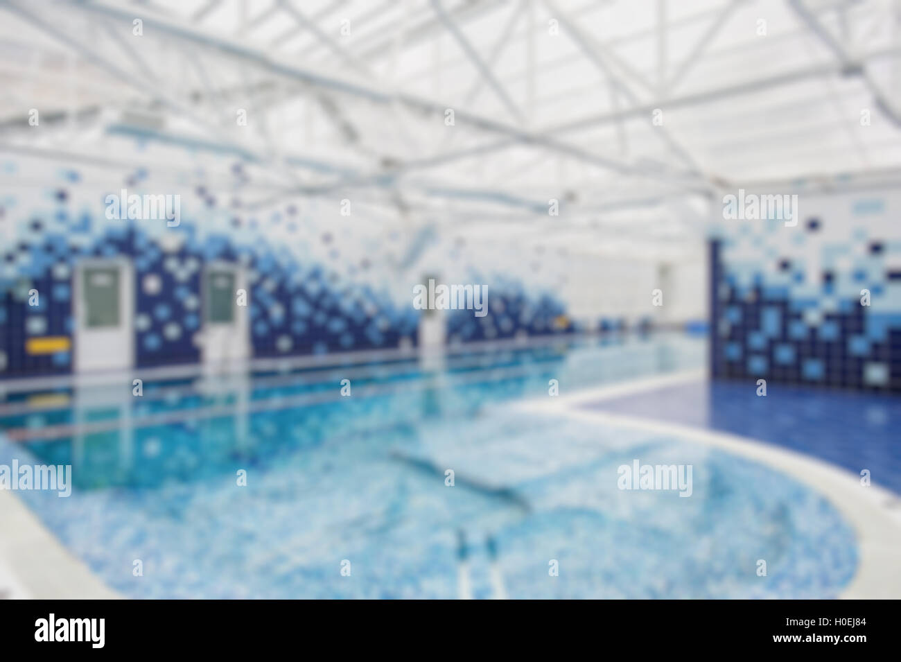 Modern indoor light swimming pool decorated with blue tiles. Blur ...