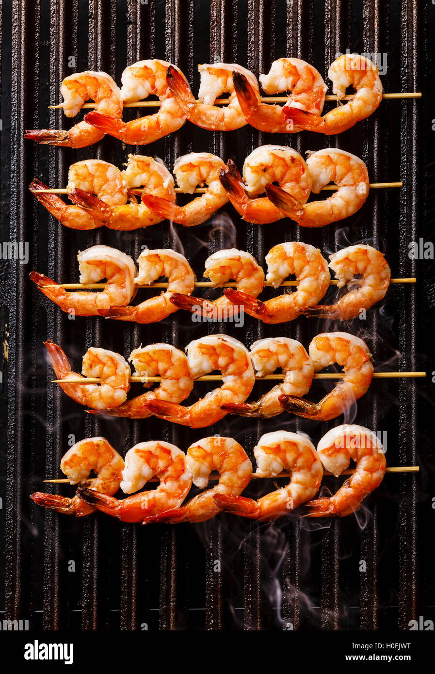 Grilled fried Prawns on skewers on black cast iron grill background ...