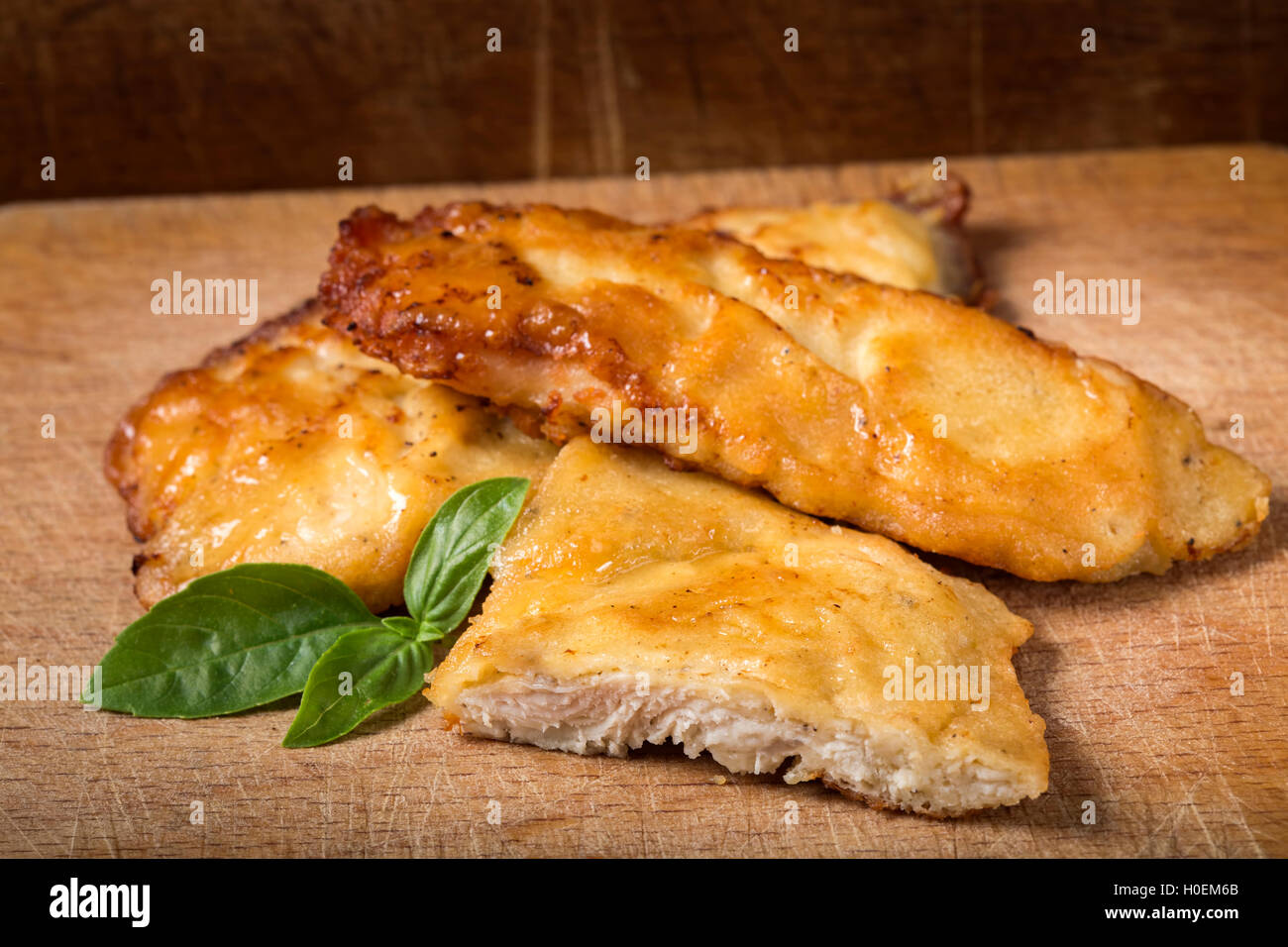 Fried chicken schnitzel on wood with basil Stock Photo - Alamy