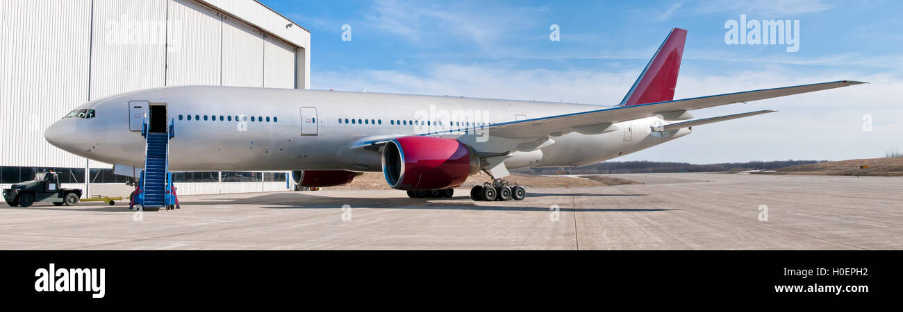 Big passenger airplane red and white parked near hangar Stock Photo - Alamy