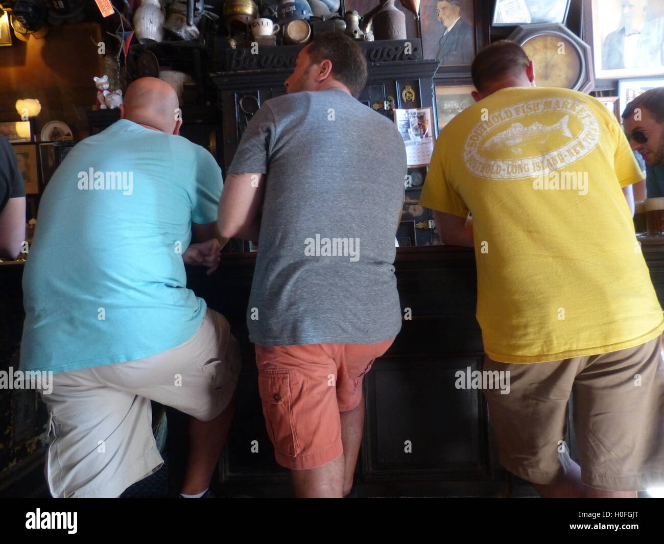 Guests in colorful shirts lean over bar while drinking beer Stock Photo ...