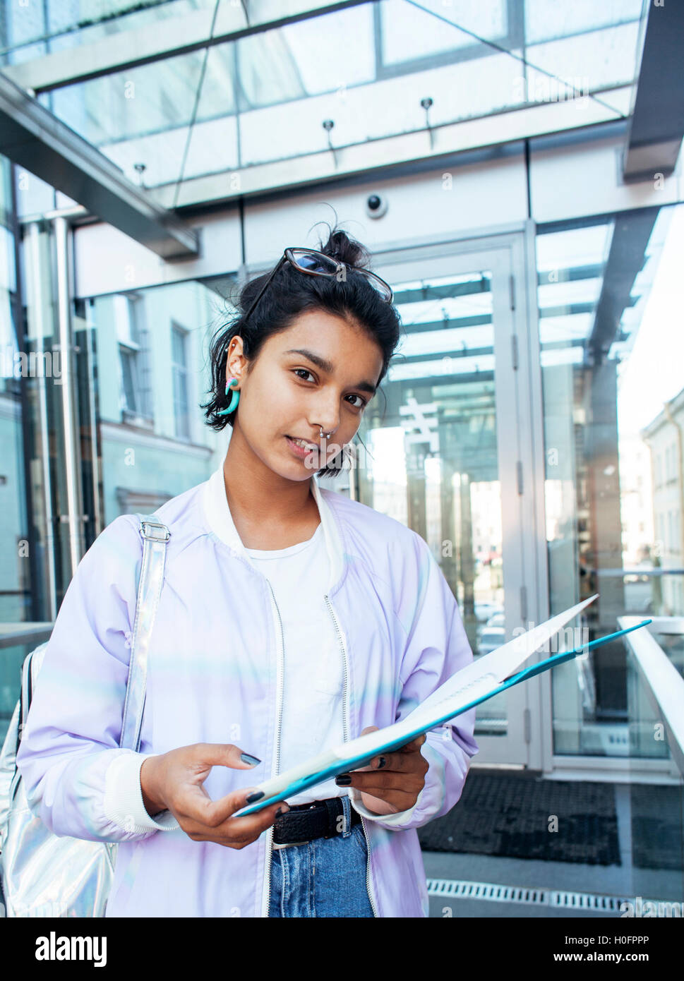 young cute modern indian girl at university building sitting on stairs ...
