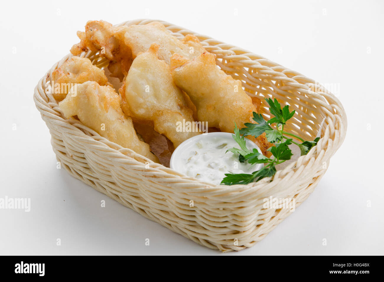 Cod in beer batter with tartar sauce in bamboo basket on white ...