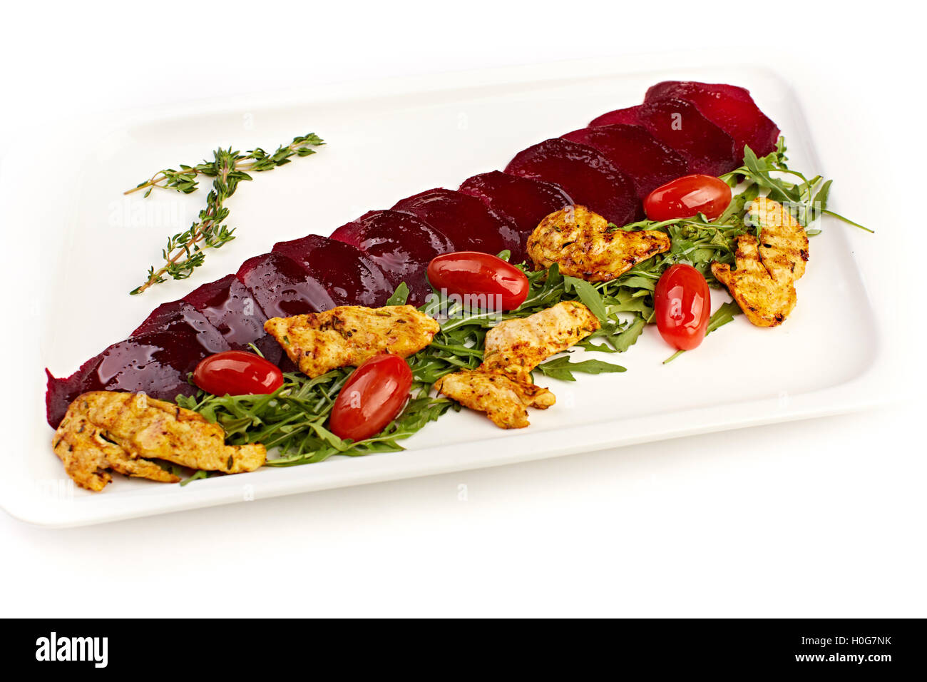 Fried chicken with beetroot, tomatoes and herbs on white plate Stock ...