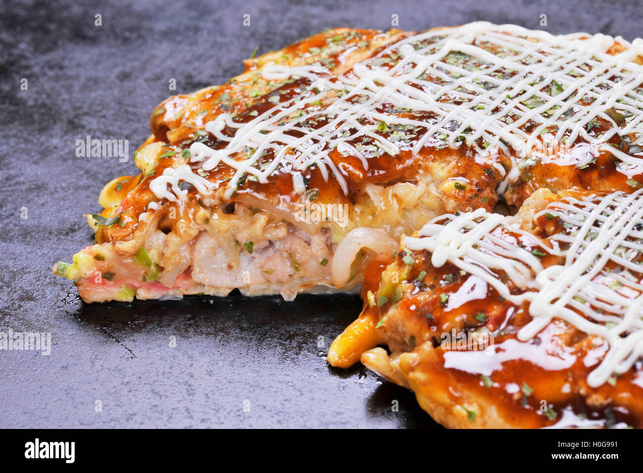 Traditional Japanese okonomiyaki pancake on hot black pan Stock Photo ...