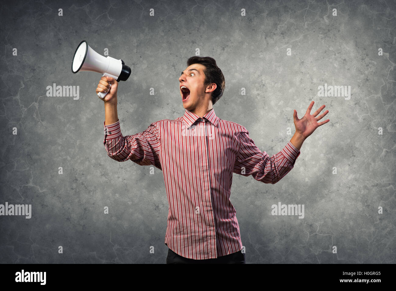 Portrait of a young man shouting using megaphone Stock Photo - Alamy