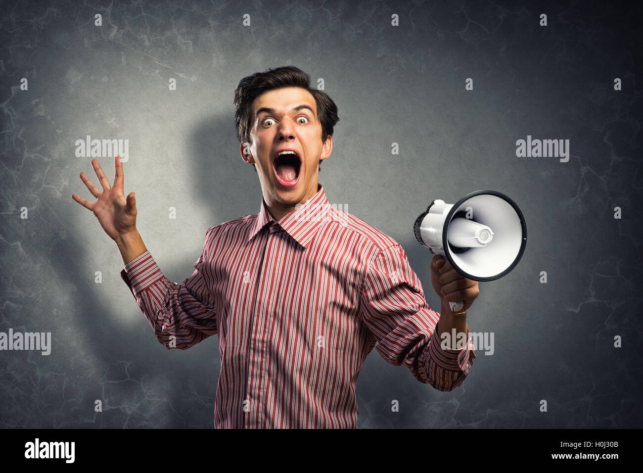Portrait of a young man shouting using megaphone Stock Photo - Alamy