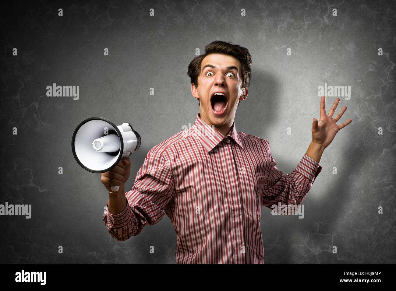 Portrait of a young man shouting using megaphone Stock Photo - Alamy