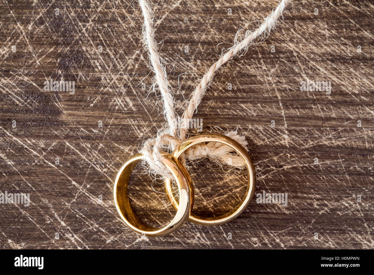 Wedding rings hanging on rope over wooden background Stock Photo - Alamy