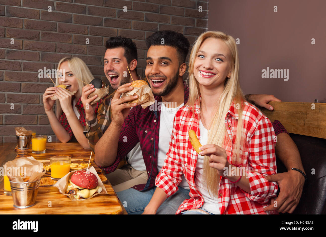 People Group Eating Fast Food Burgers Sitting At Wooden Table In Cafe ...
