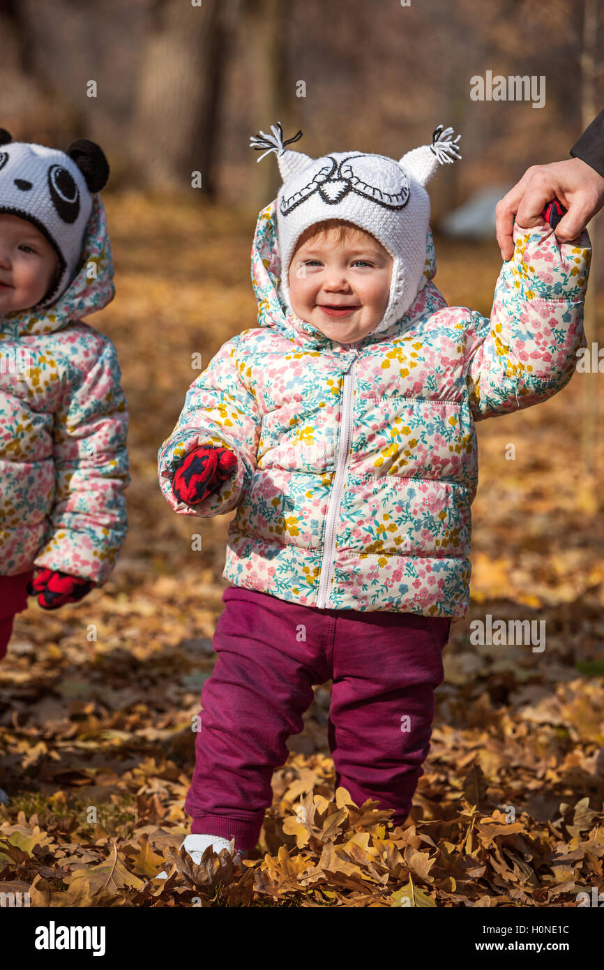 The two little baby girls standing in autumn leaves Stock Photo - Alamy