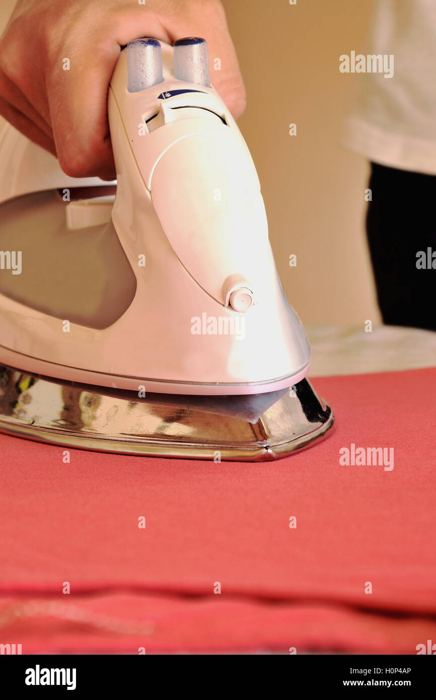 Front crop view of woman hand ironing clothes Stock Photo - Alamy