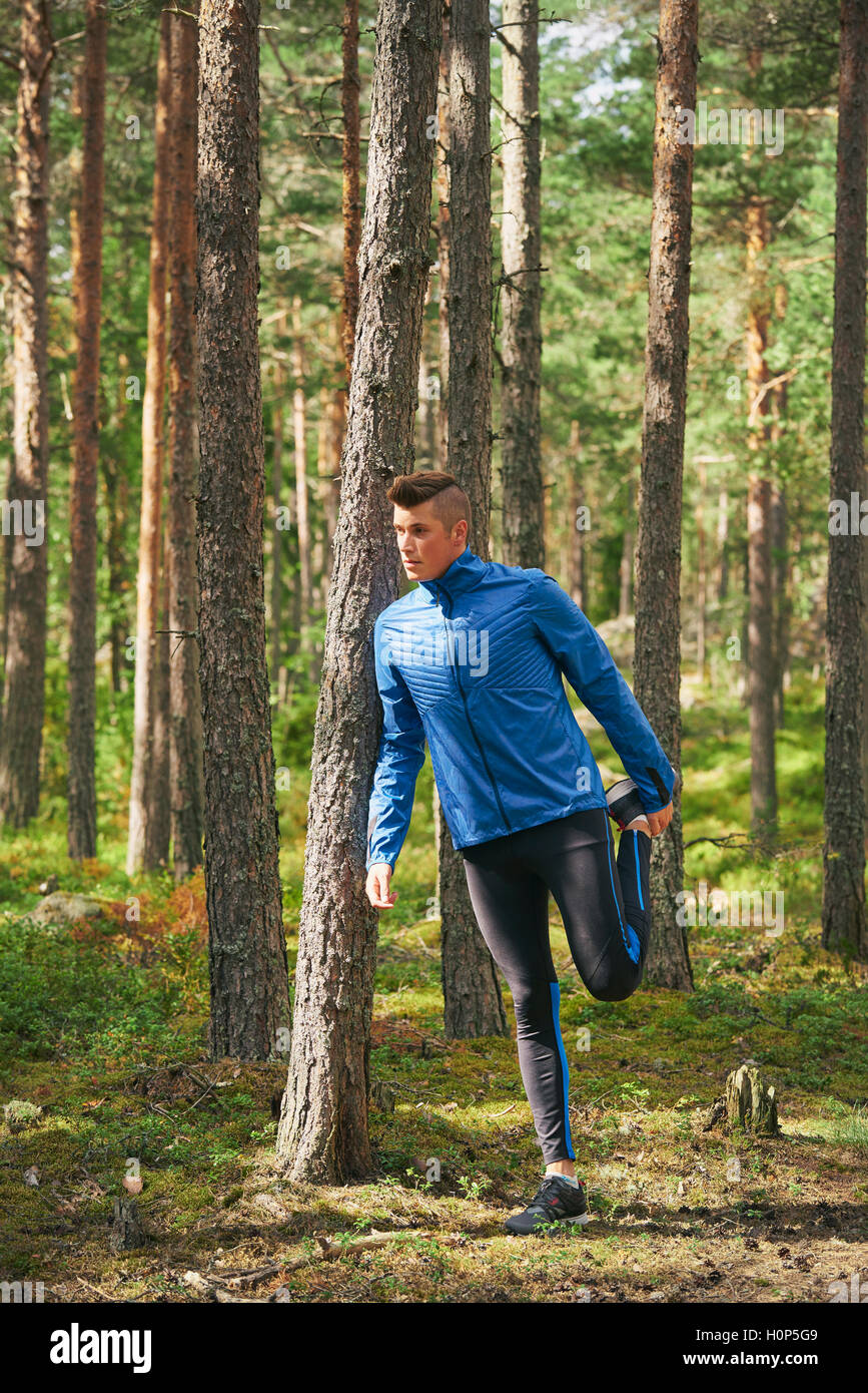runner stretching leg tree woods Stock Photo - Alamy