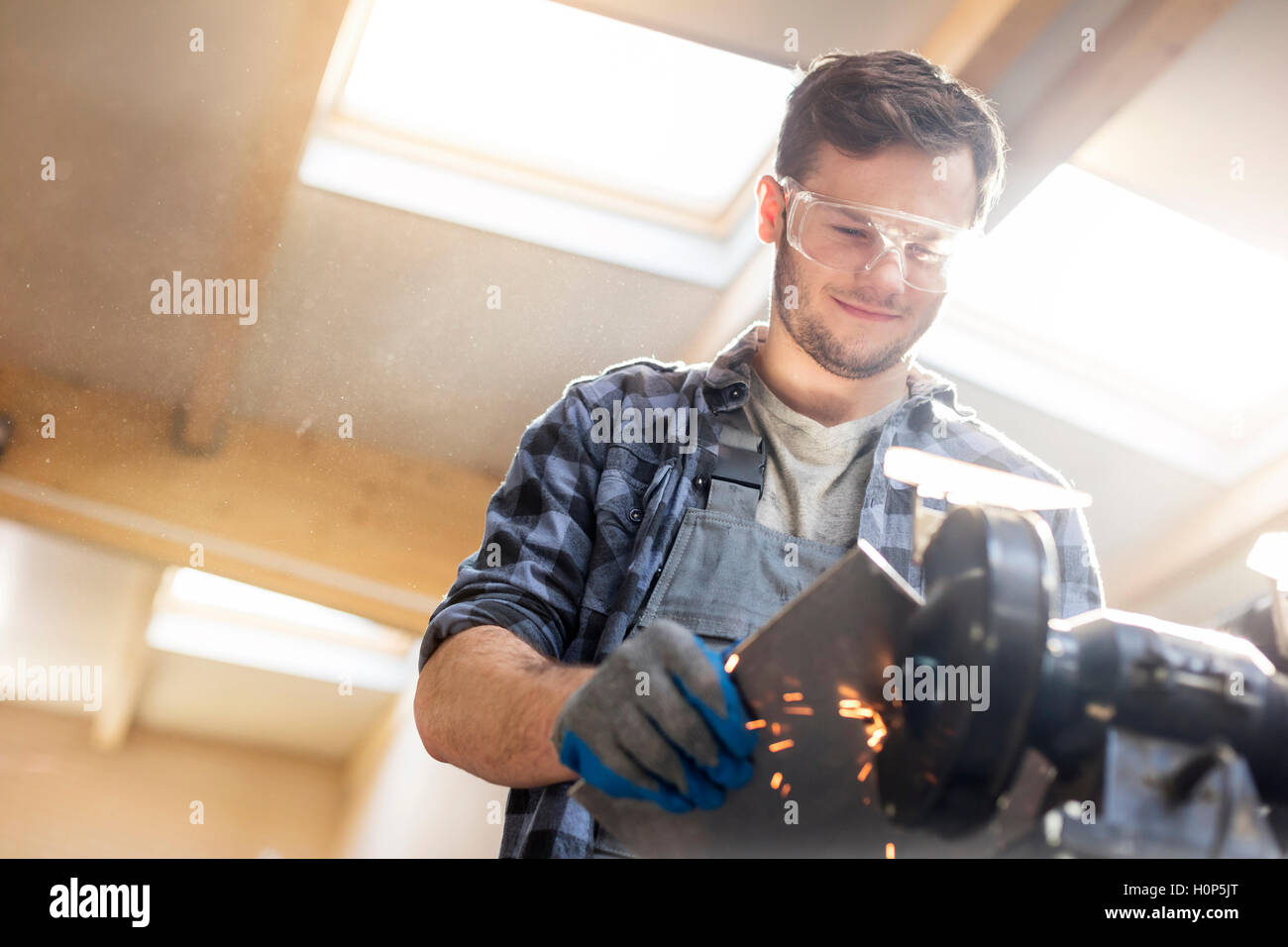 smiling metal worker using sander workshop Stock Photo - Alamy